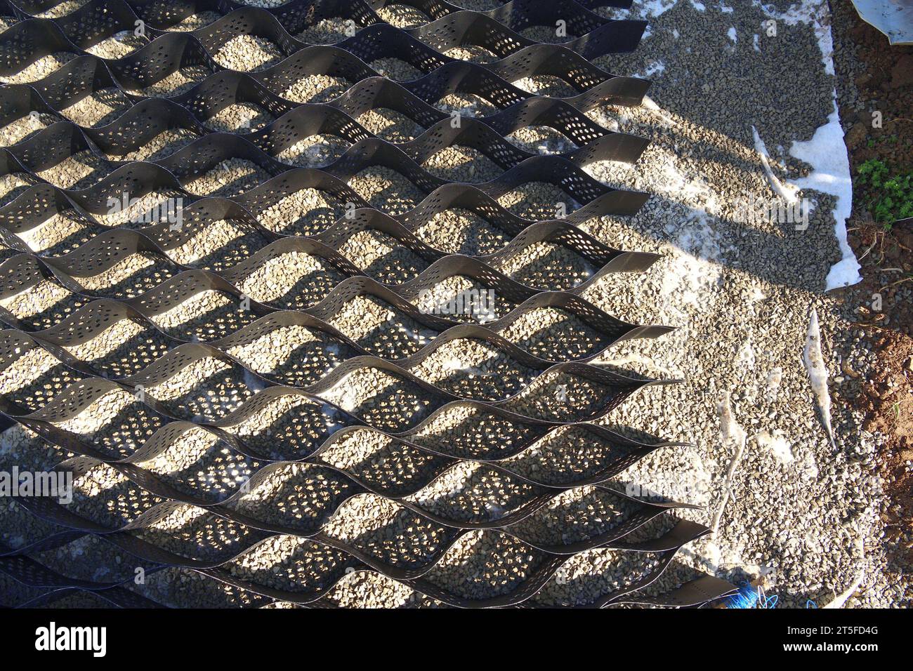 A bricklayer builds a parking for car using foil and crushed stone ...