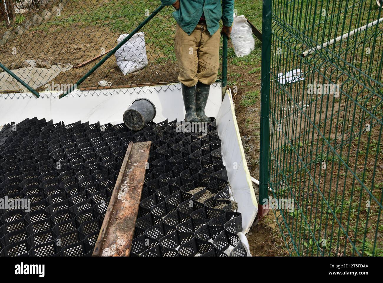 Pouring crushed stone into the plastic net and compacting the plastic ...