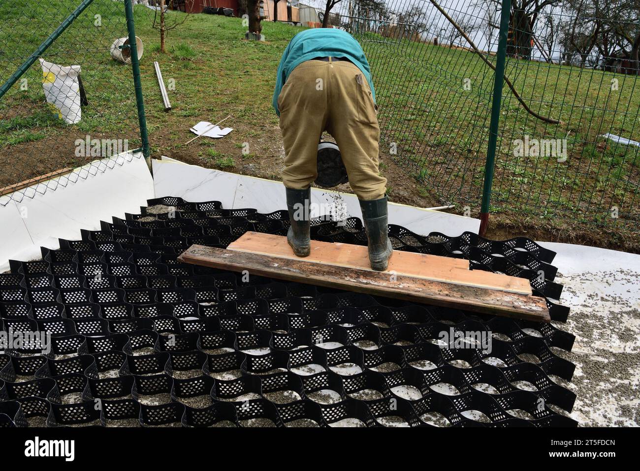 Pouring crushed stone into the plastic net and compacting the plastic ...