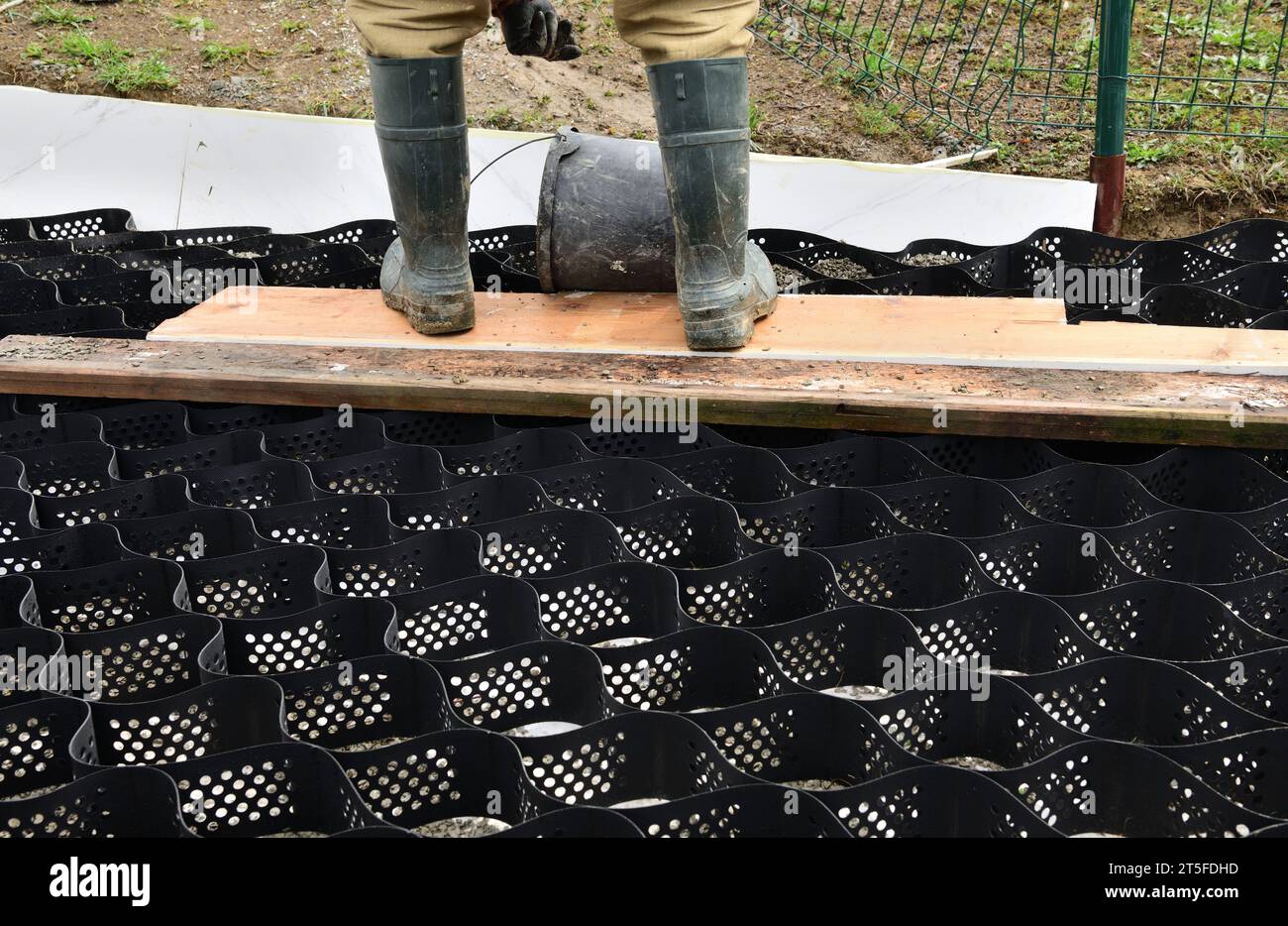 Pouring crushed stone into the plastic net and compacting the plastic ...