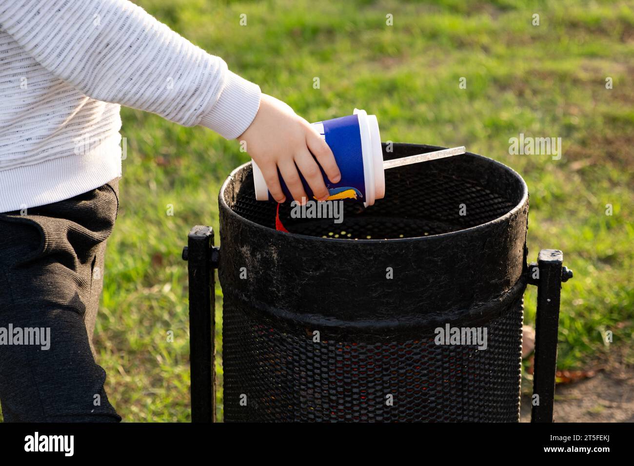 A child throws a plastic cup in the trash. Garbage recycling and ...