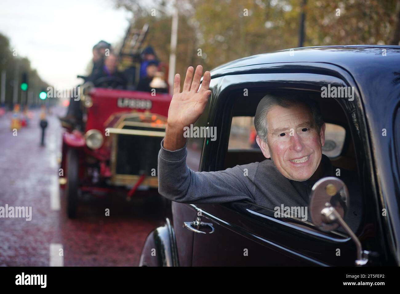 A participant wearing a King Charles III mask drives down the Mall in ...