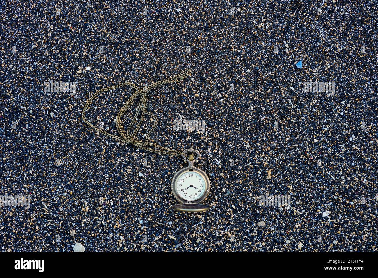 Gold color pocket watch lying on the sand. With copy space for text ...