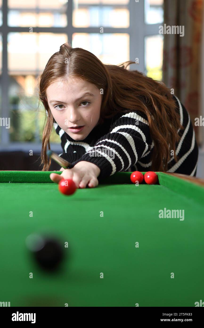 Teenage girl playing traditional pub game of bagatelle in lounge at ...