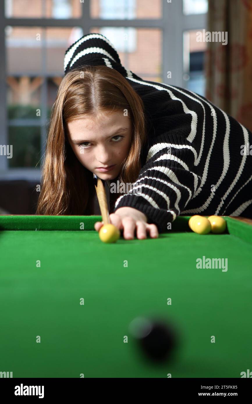 Teenage girl playing traditional pub game of bagatelle in lounge at ...