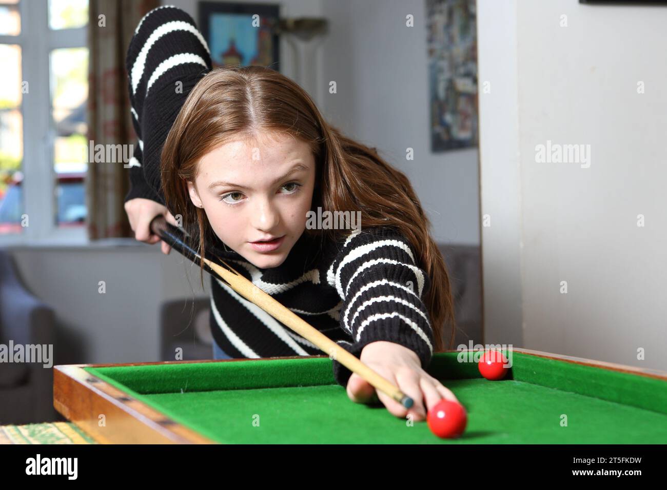 Teenage girl playing traditional pub game of bagatelle in lounge at ...