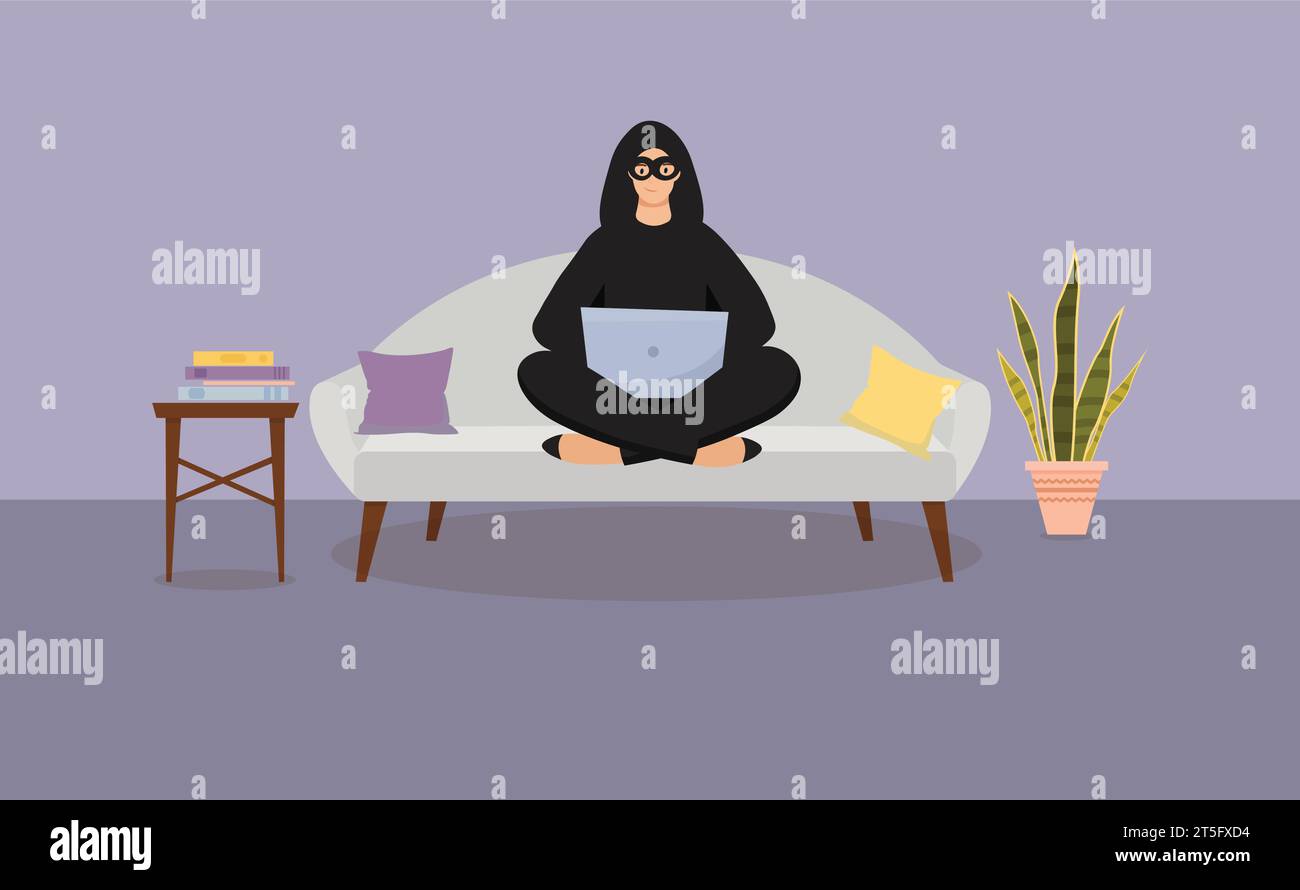 Hacker in a black mask with a computer. The cybercriminal is holding a ...