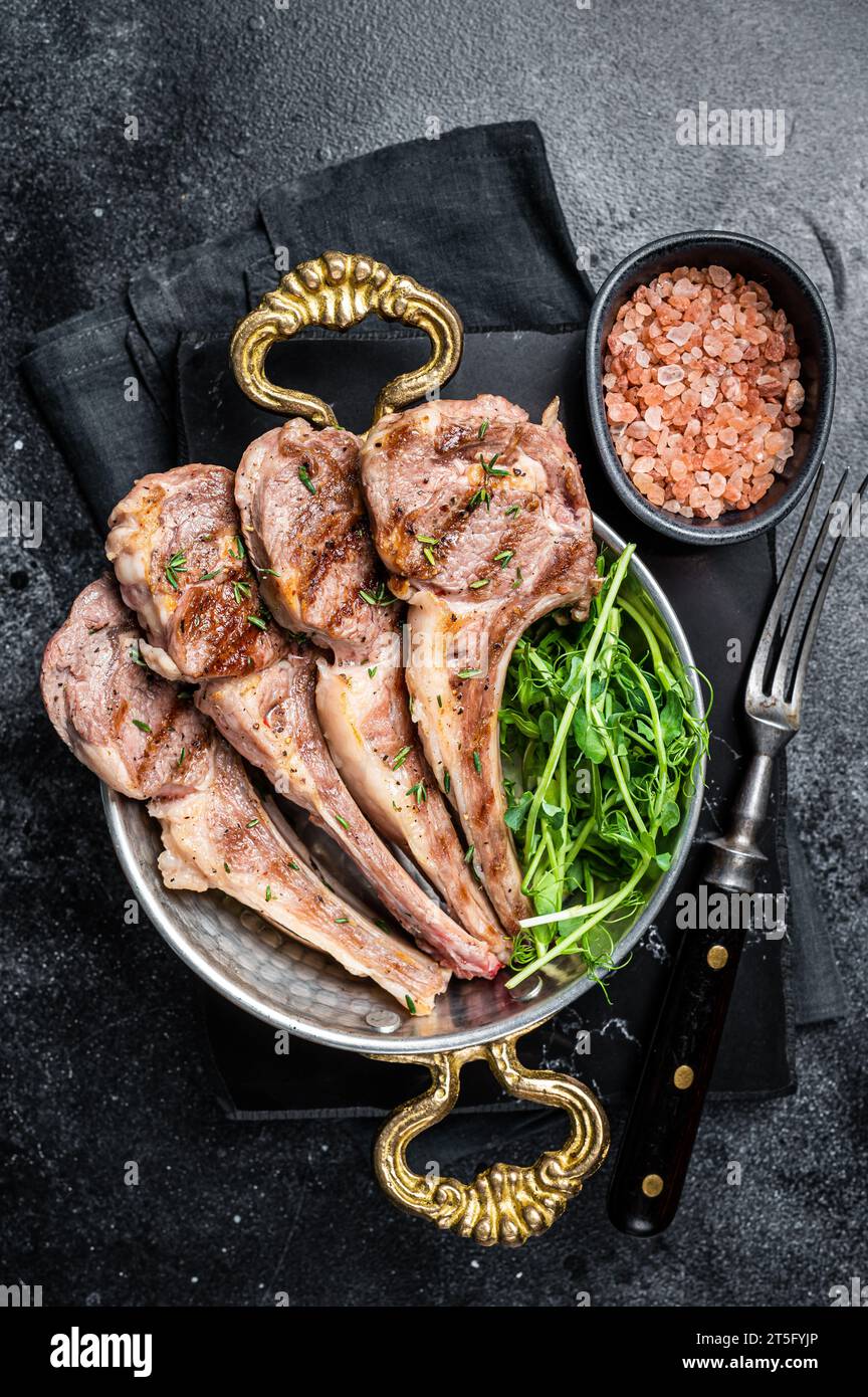 Grilled Lamb mutton Chops steaks in a skillet with green salad. Black ...