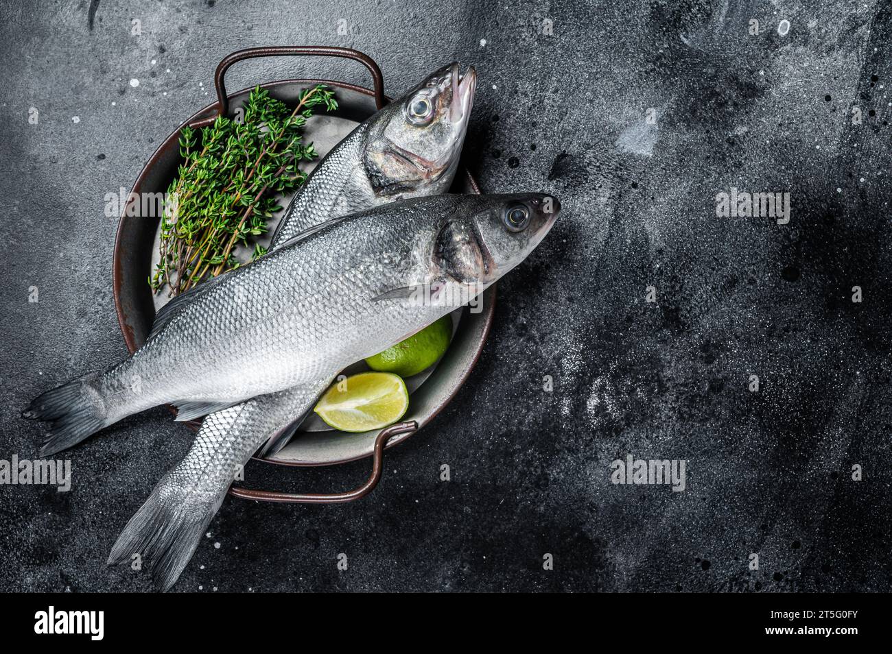 Fresh Raw Sea Bass, Labrax fish with herbs and lime. Black background ...