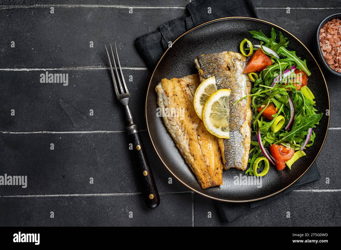Roasted sea bass fillet with salad, Branzino fish. Black background ...