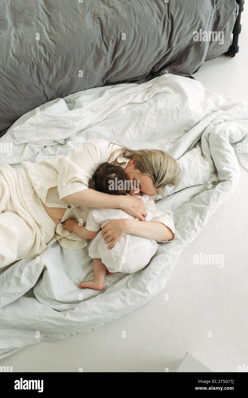 The little girl lay down on her mother and wants to sleep. Mom tenderly ...