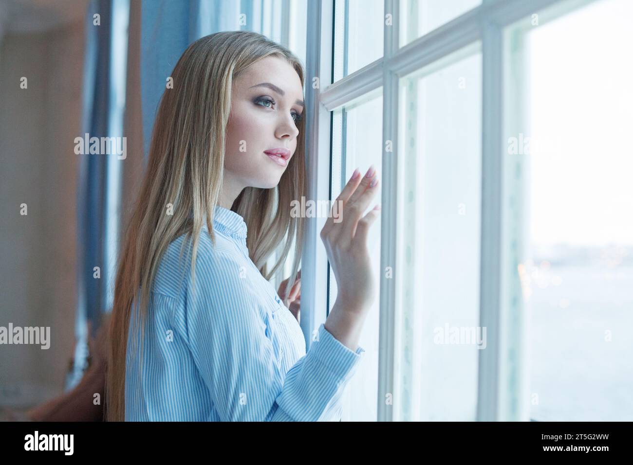 Perfect young blonde woman looking out the window, indoor portrait ...