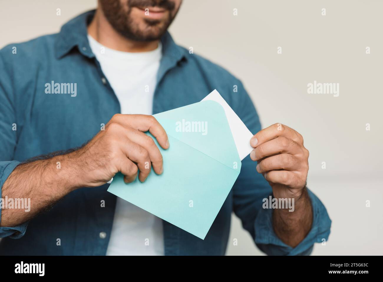 Unrecognizable middle aged man opening envelope receiving a letter ...