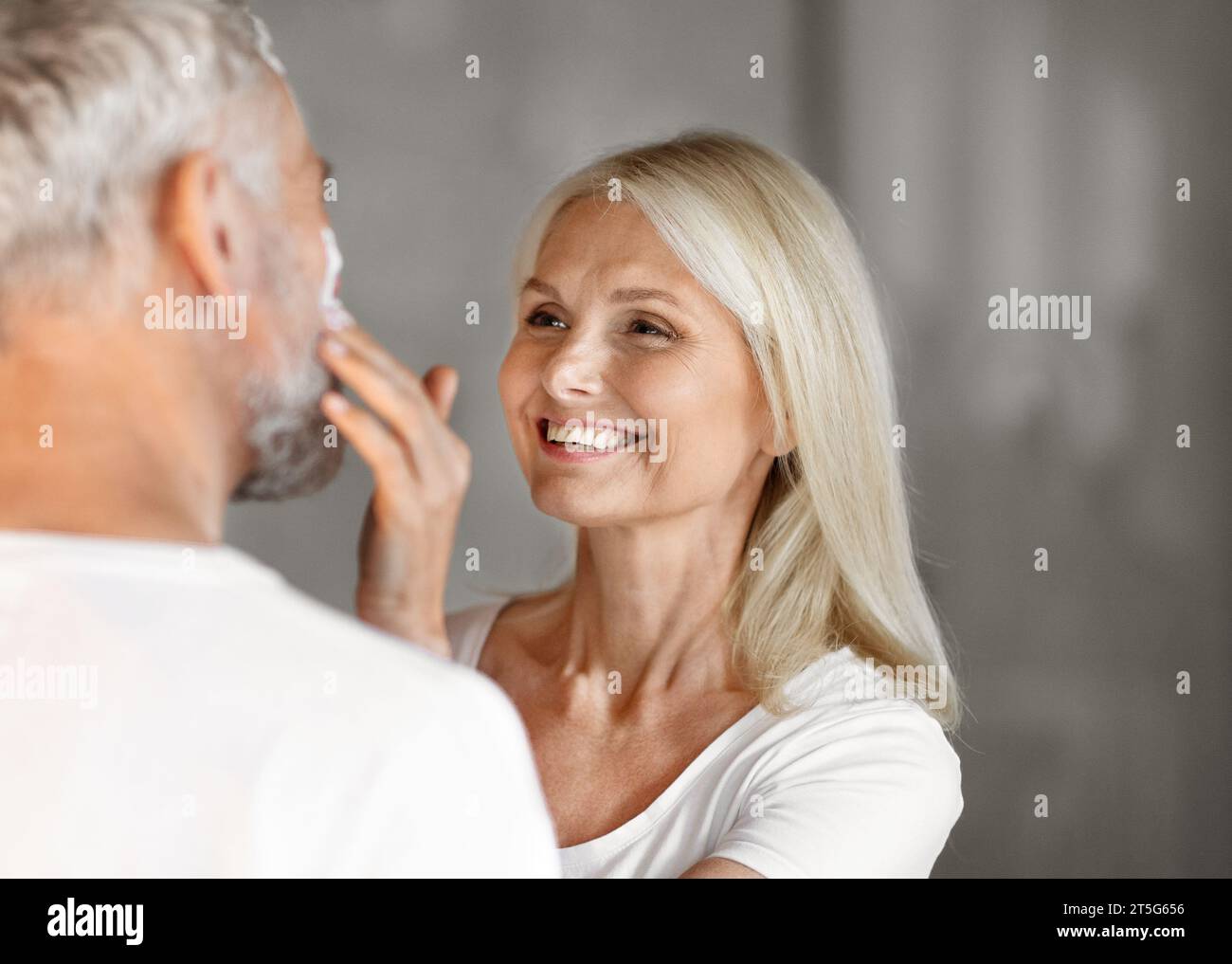 Family Skincare. Mature Woman Applying Moistusing Cream To Her Husband ...