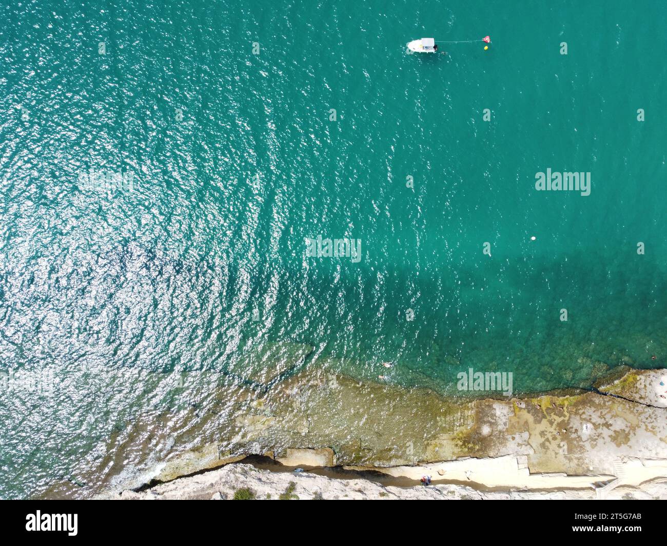 Small pleasure boat sailing close by to the rocky shoreline in a ...