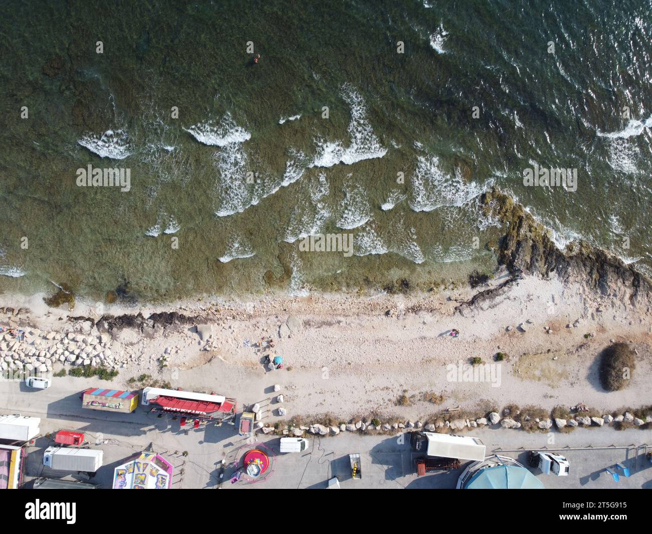 Aerial view of a quiet seaside fair with waves washing up onto the ...