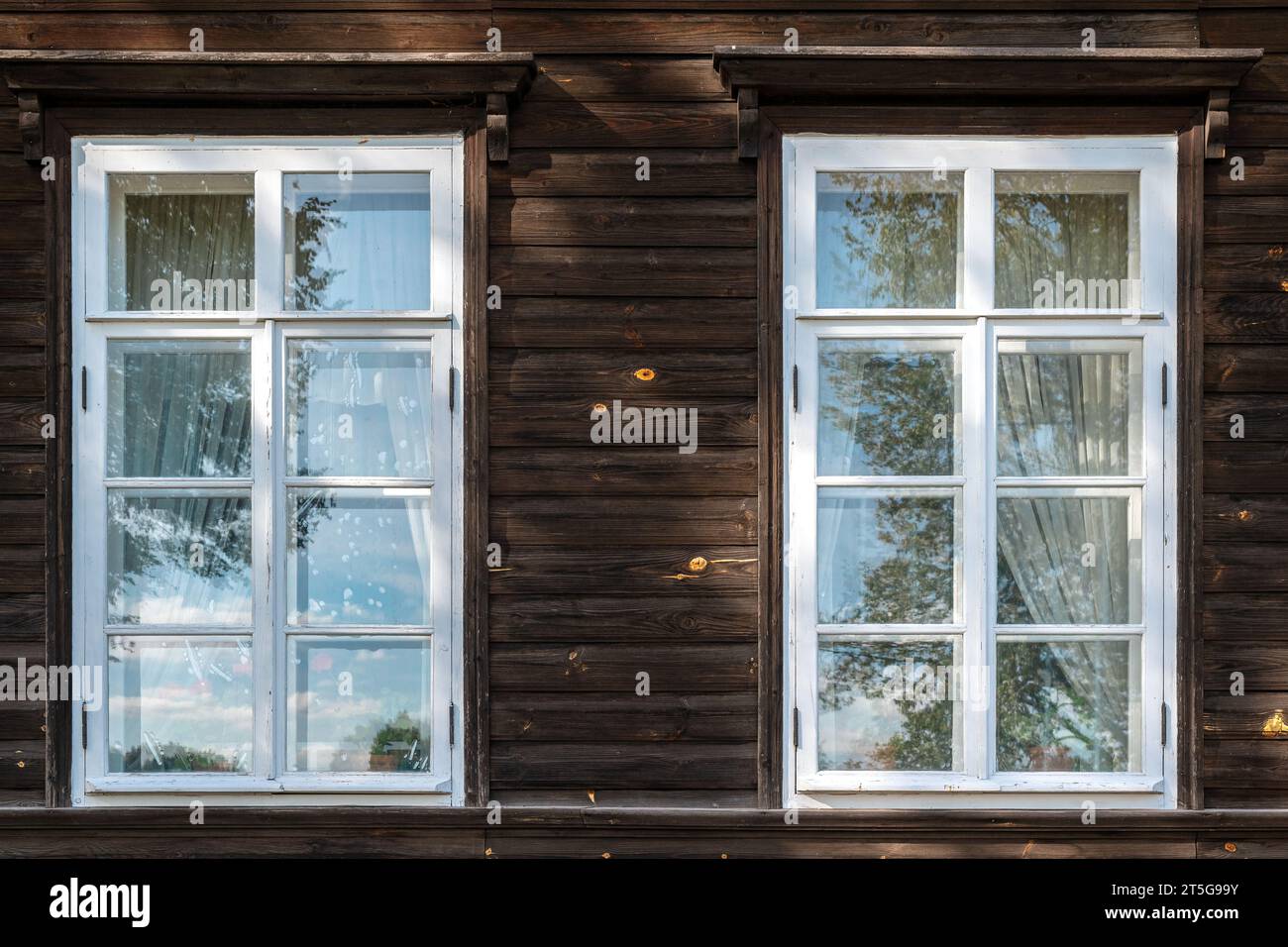 Two rectangular windows with a visor and white frames on a wooden wall ...
