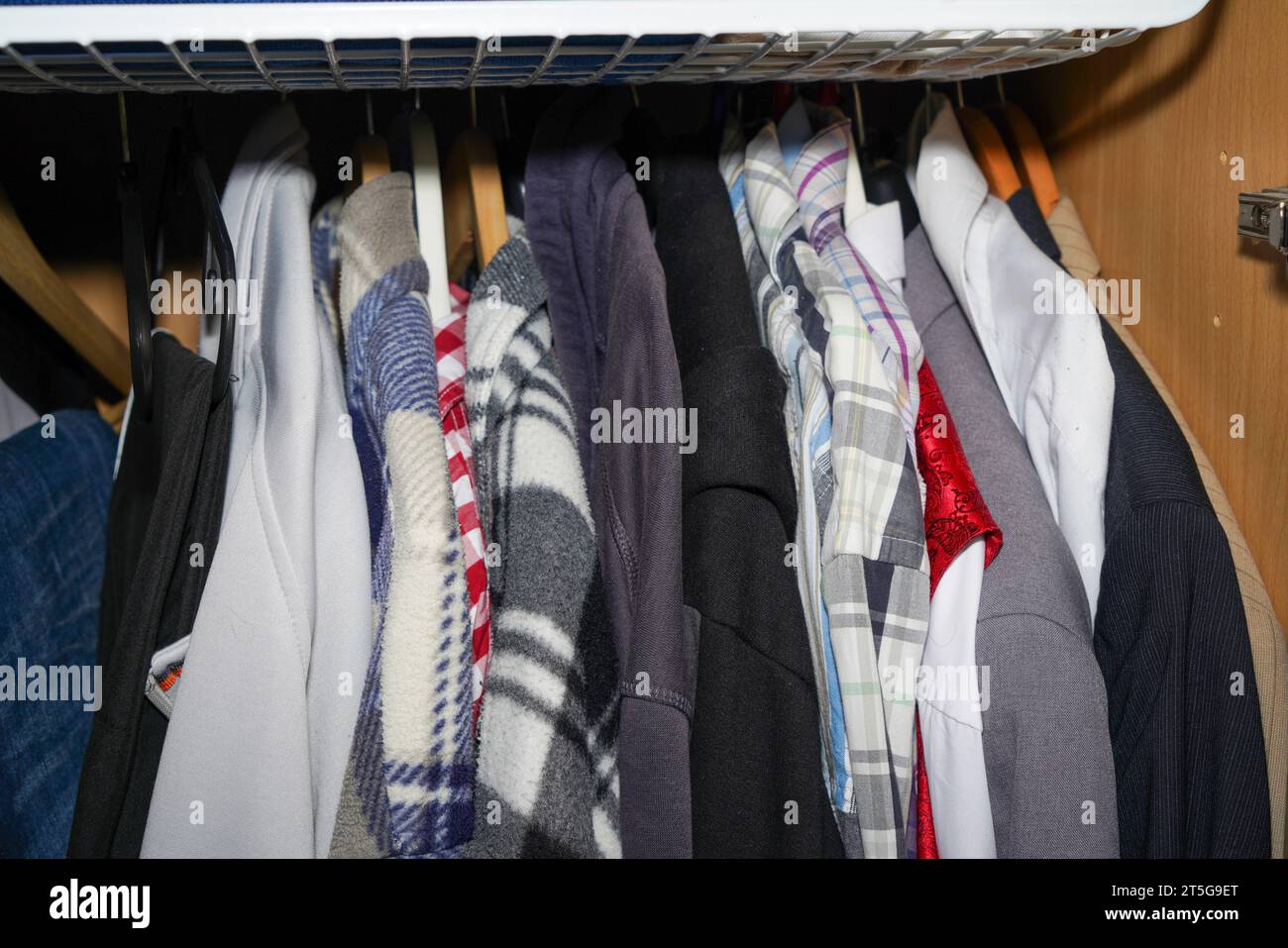 Wardrobe overflowing and colorfully mixed with jackets and pants ...