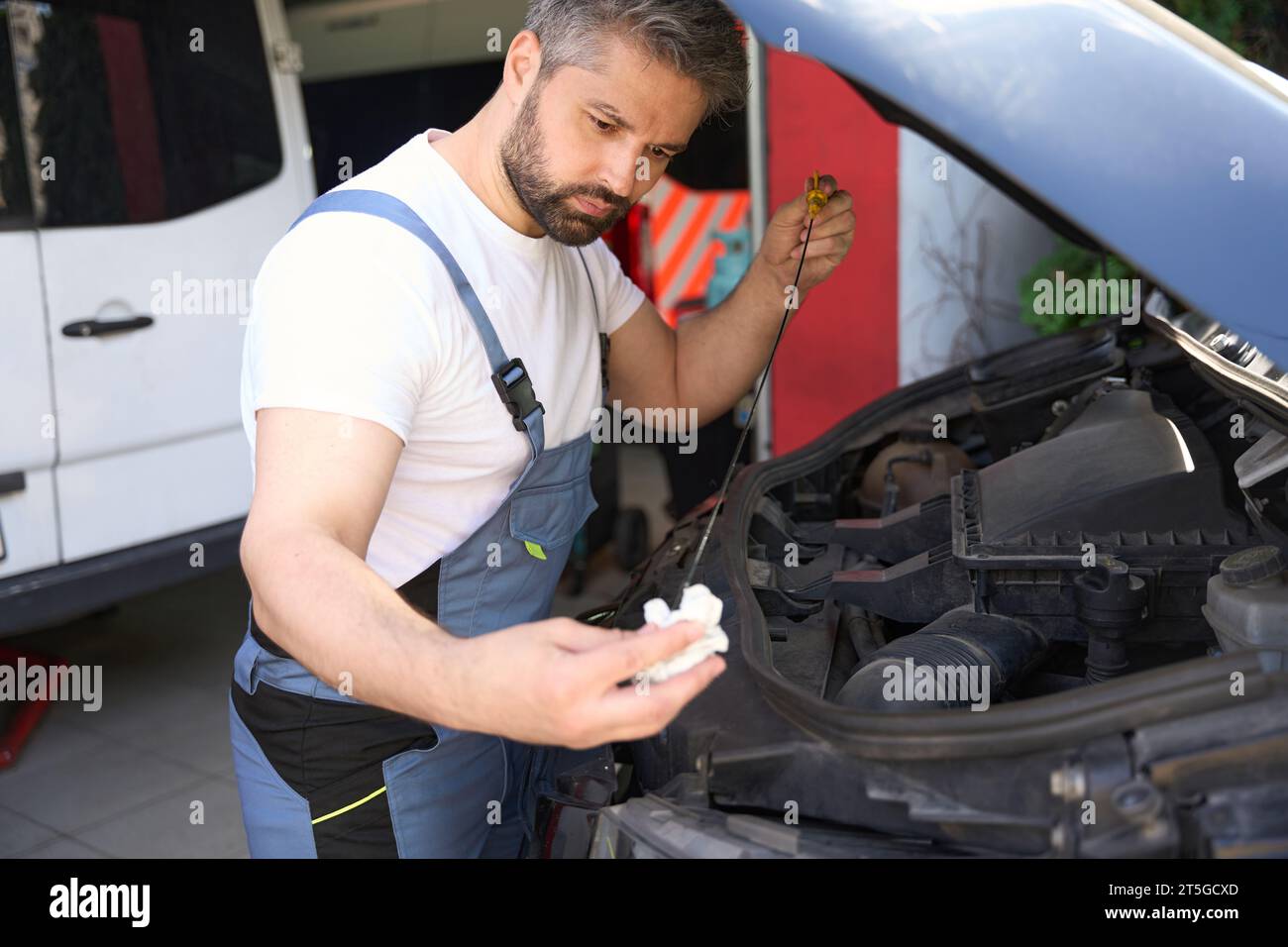 Focused mechanic preparing for measuring oil level in automotive engine ...