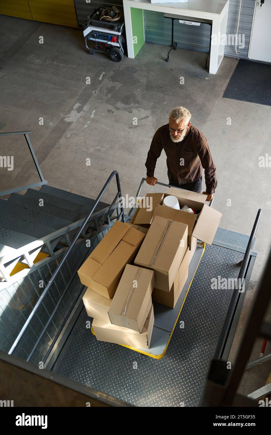 Gray-haired male lifts cart with things on a freight elevator Stock ...