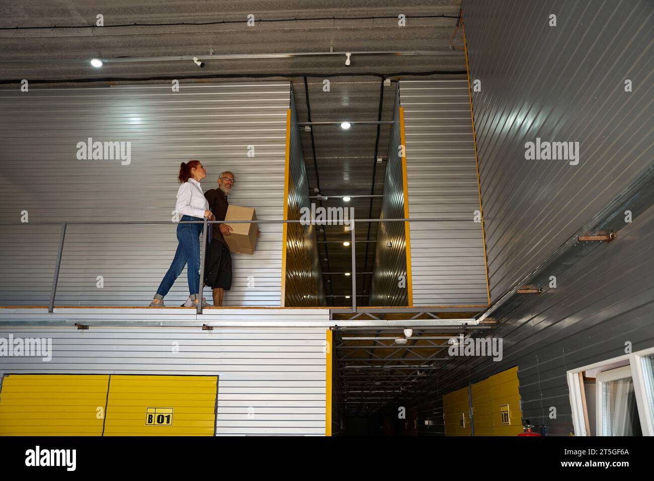 Client with a box and a manager walk through warehouse Stock Photo - Alamy