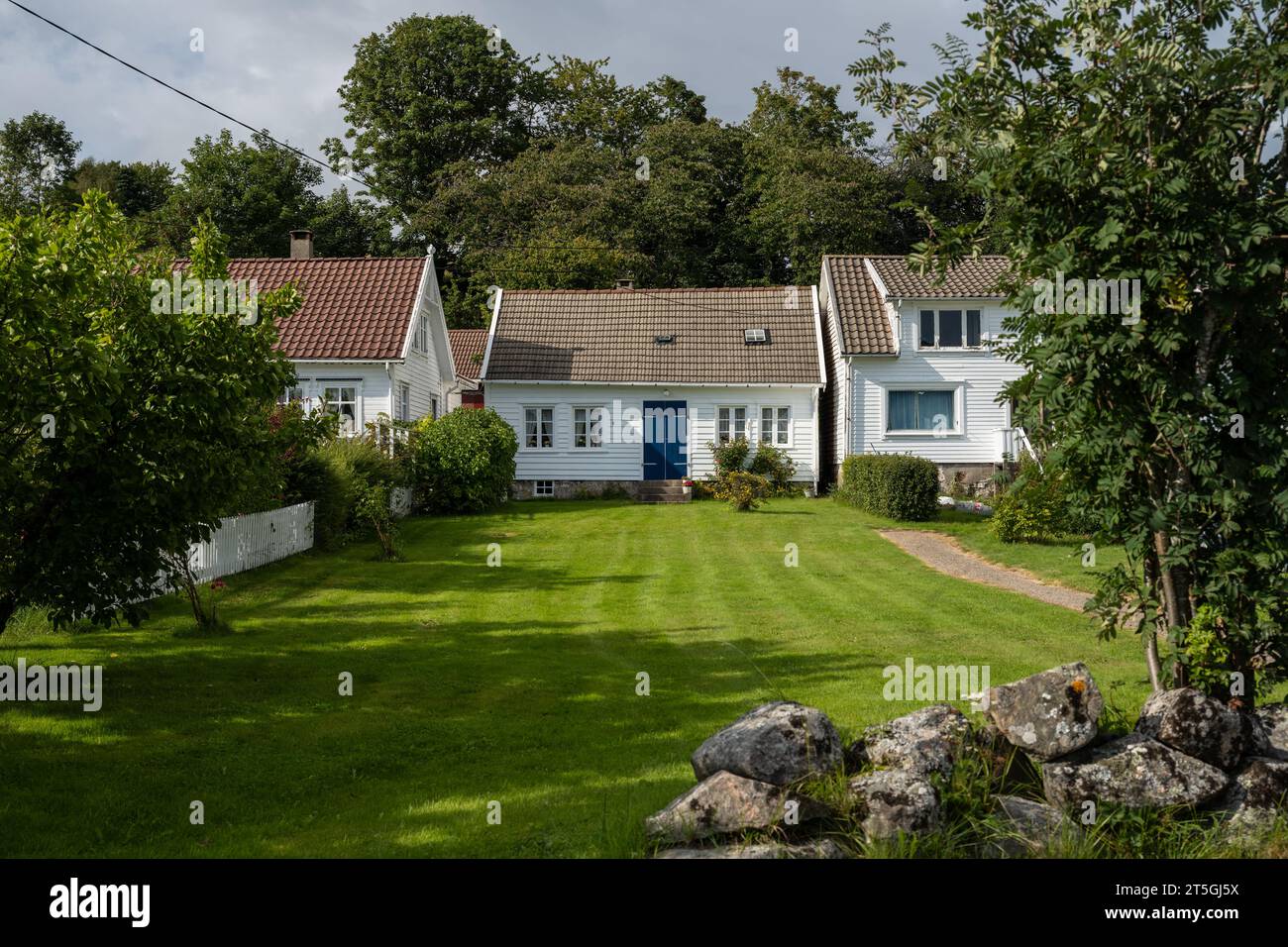 Small white wooden house in between two houses Stock Photo - Alamy
