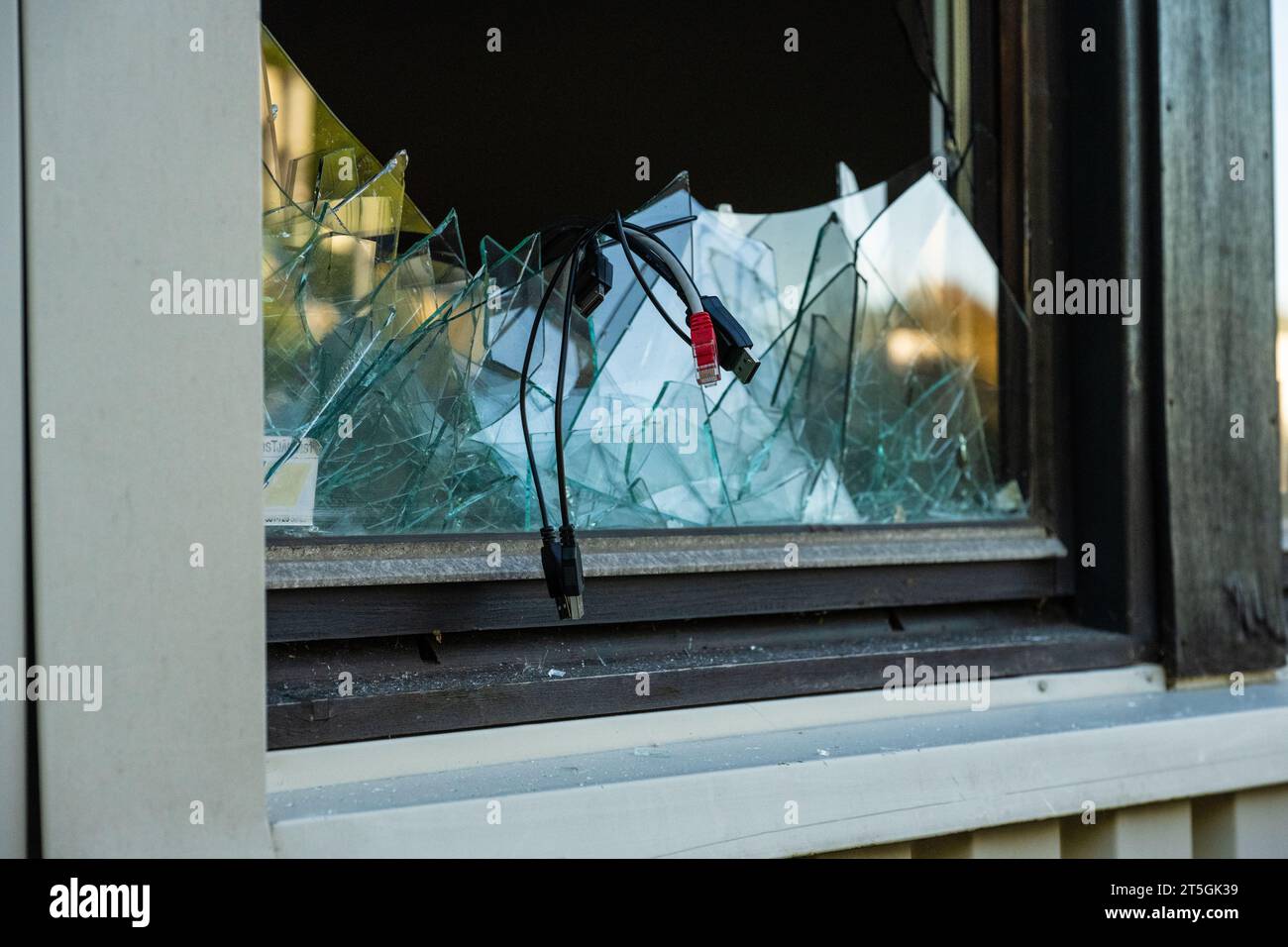 Computer cables hanging out of a broken window after a break in and ...