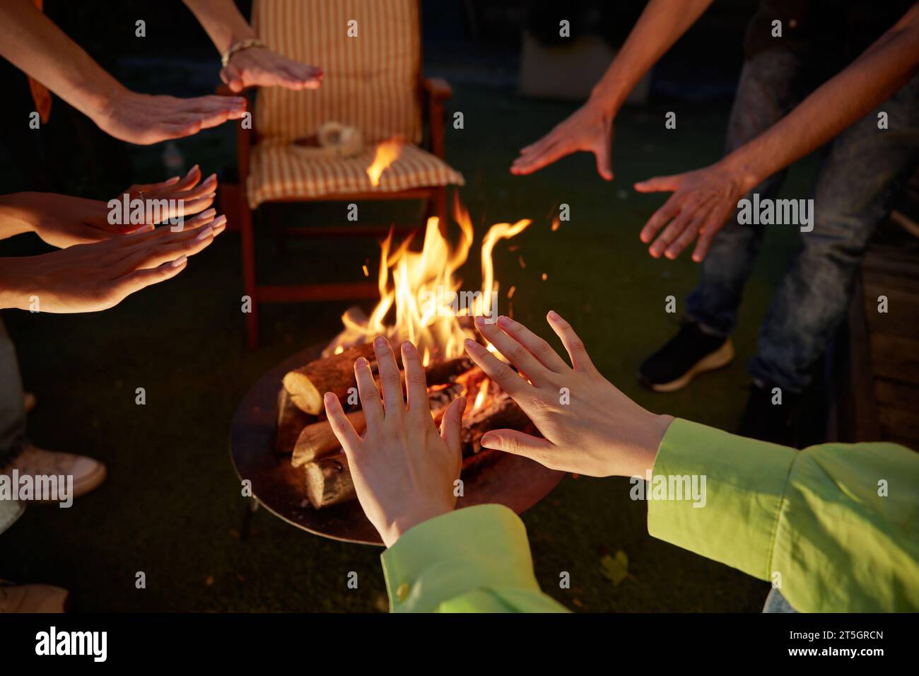 Group of young people warming hands over burning campfire closeup Stock ...