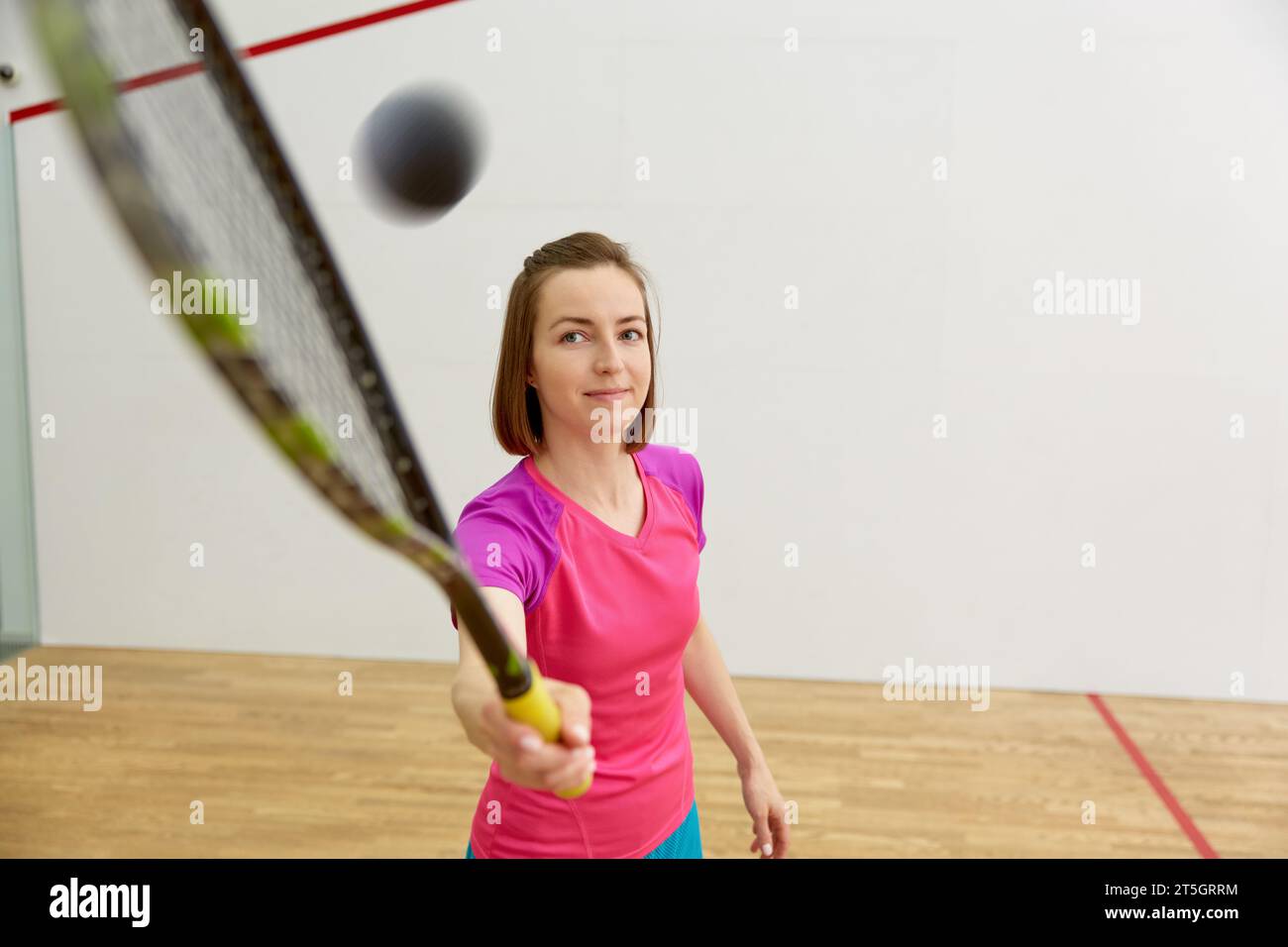 Closeup view on female athlete with racquet playing squash at fit club ...