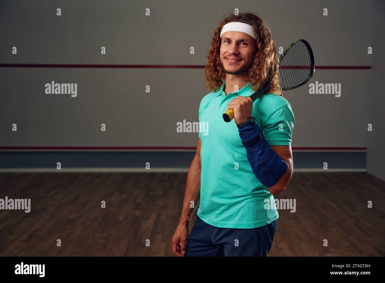 Portrait of male squash player standing with racket ready for game ...
