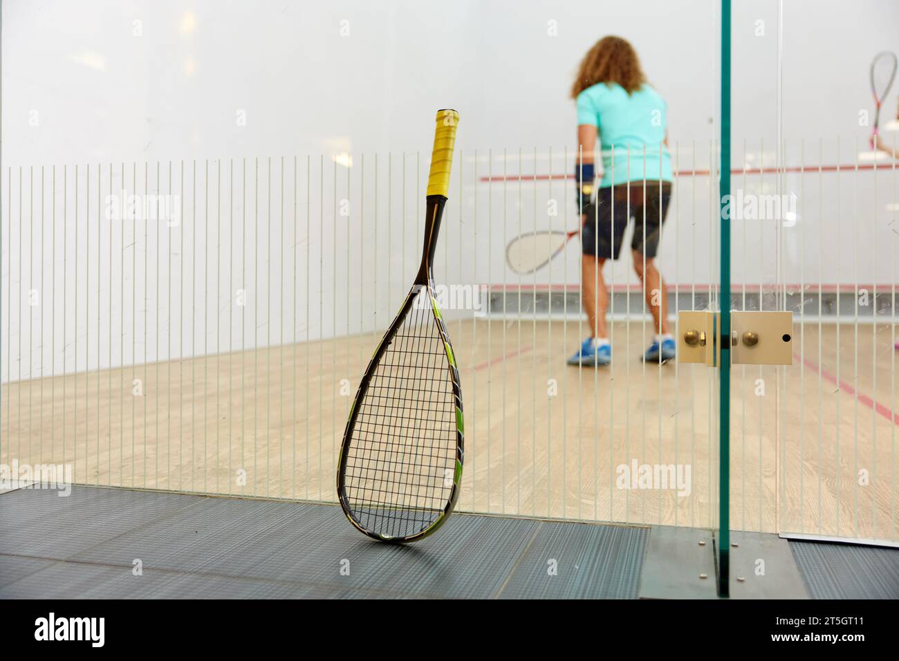 Squash racket leaned on net and sportspeople playing Stock Photo - Alamy