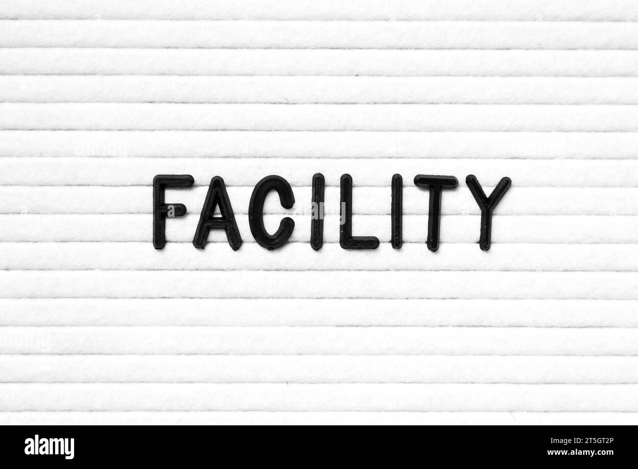 Black color letter in word facility on white felt board background ...