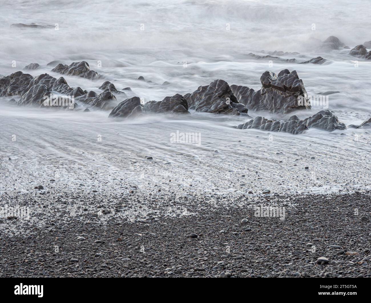 Water spray and mist over rocks on beach and shingle Stock Photo - Alamy