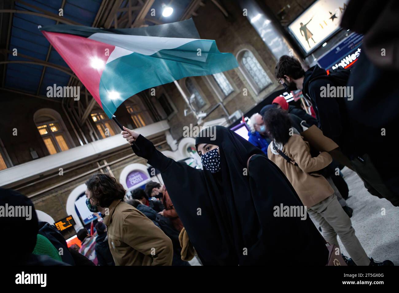 A woman waves a Palestinian flag at Charing Cross train station during ...