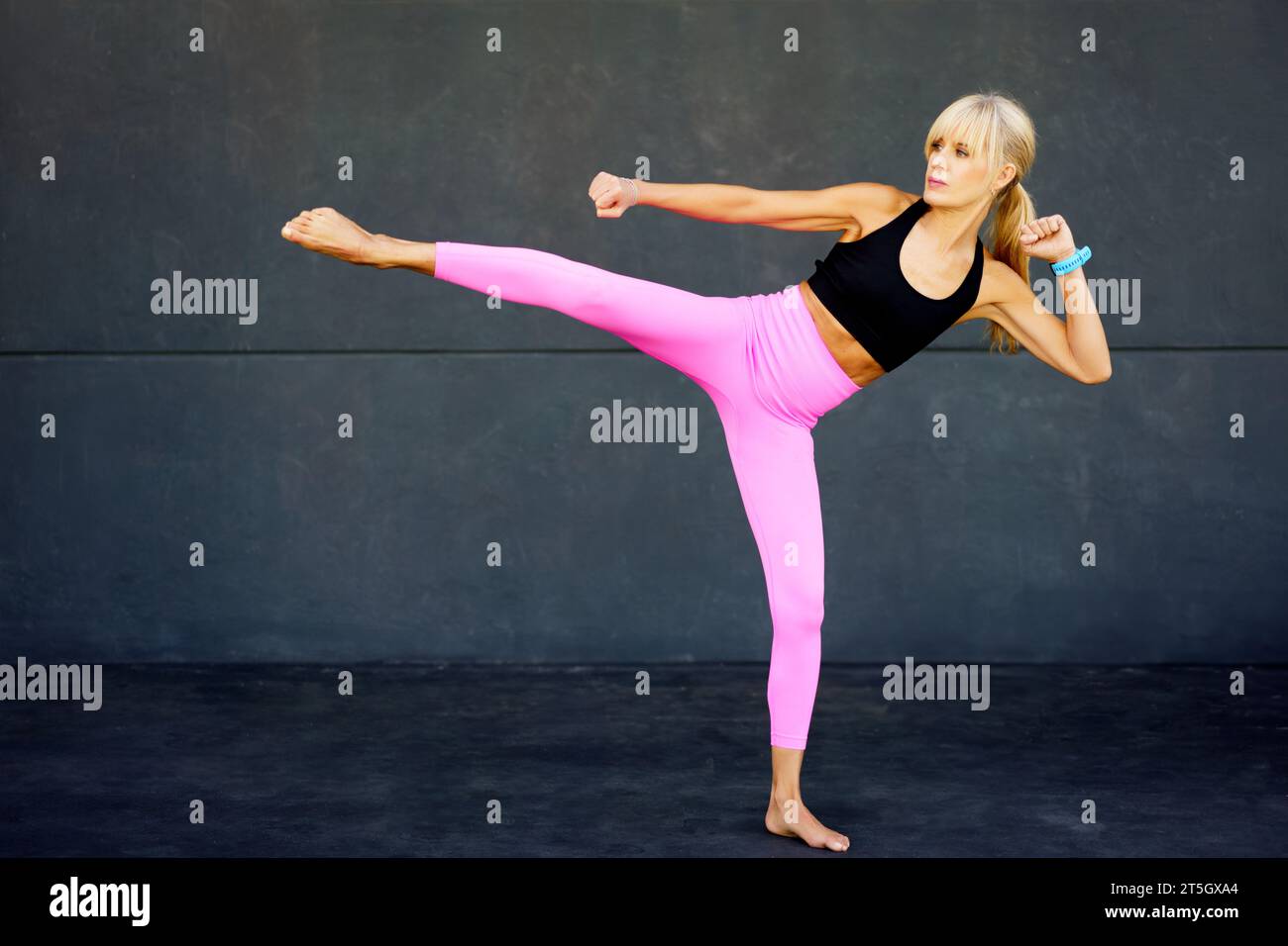 Slim fit female performing martial arts kick Stock Photo - Alamy