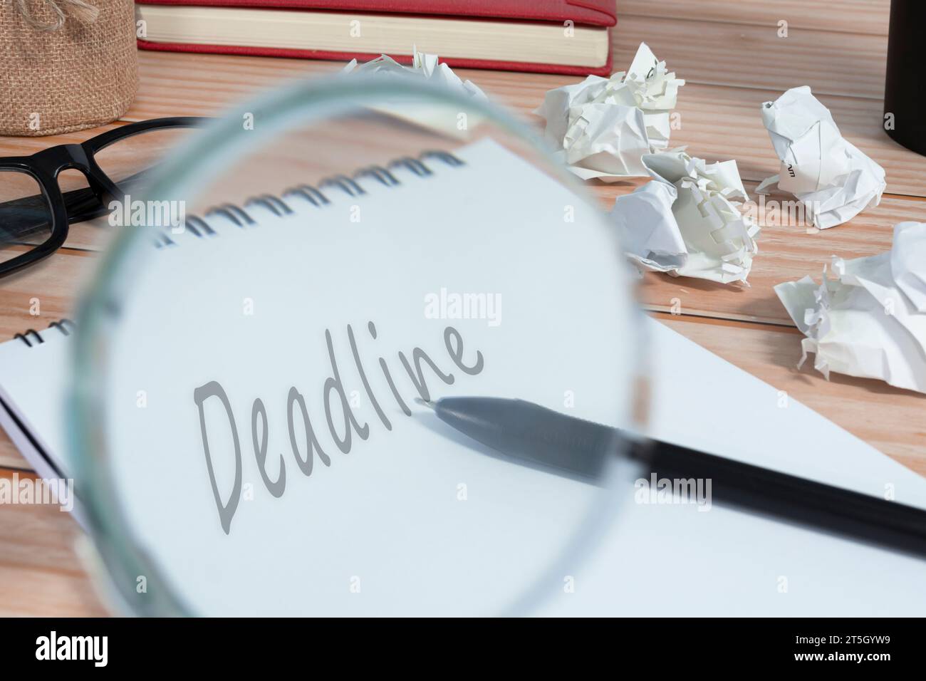 Magnifying glass on notepad with word deadline and trash paper background on office desk ...