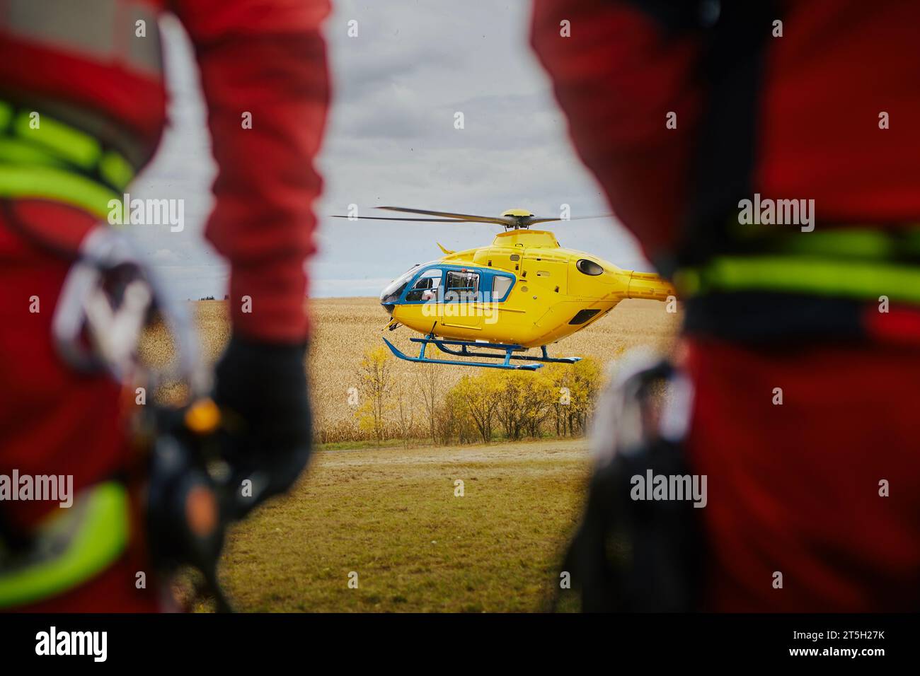 Rear view of paramedics as they looking at landing helicopter of ...