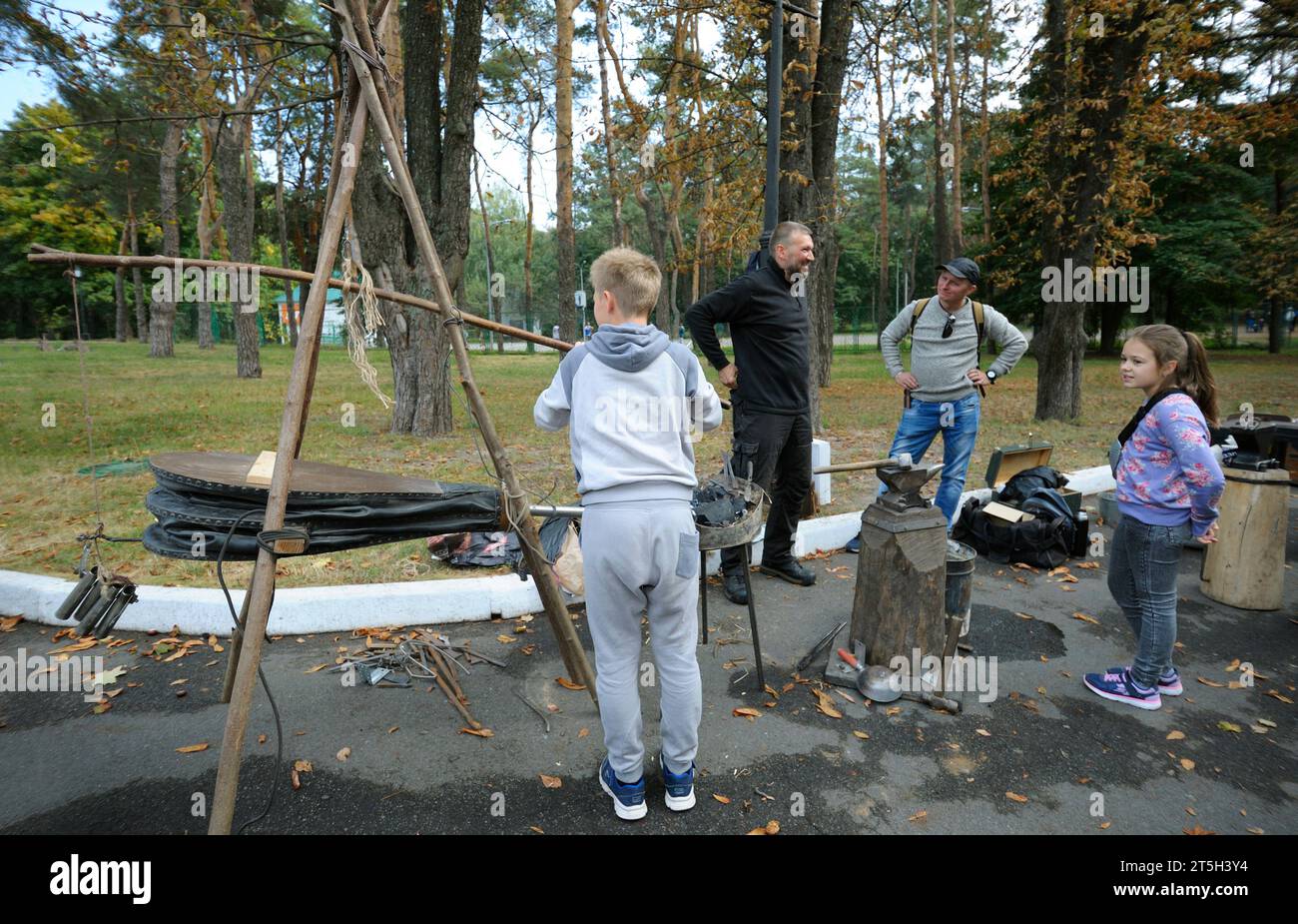 Teaching of forging. Boy pumping air to a forge using bellows, little ...