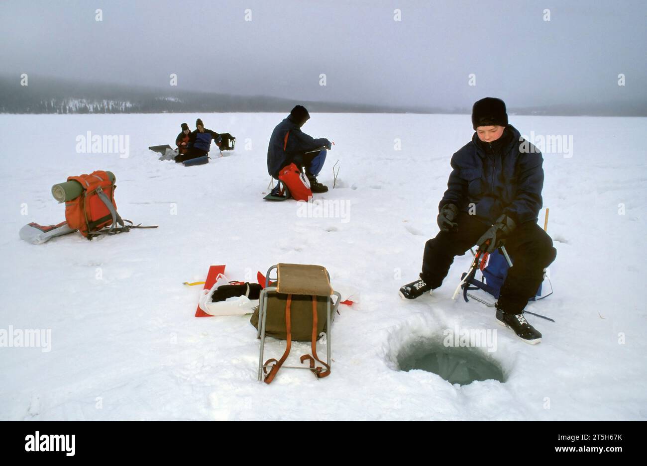 TROMSO,NORWAY - JANUARY 14 2022: Fishermen ice fishing on a frozen lake ...