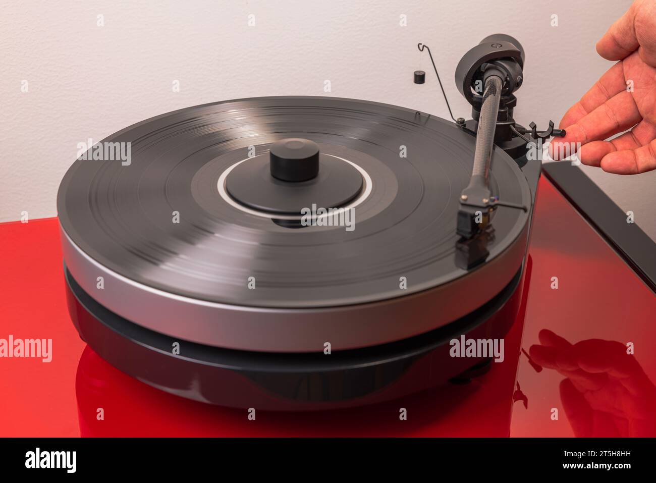 Сlose-up view of person's hand as they turn off playing vinyl record on ...
