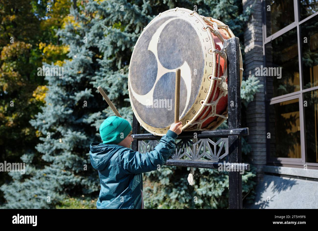 Little boy playing Japanese musical instrument taiko using drumsticks ...