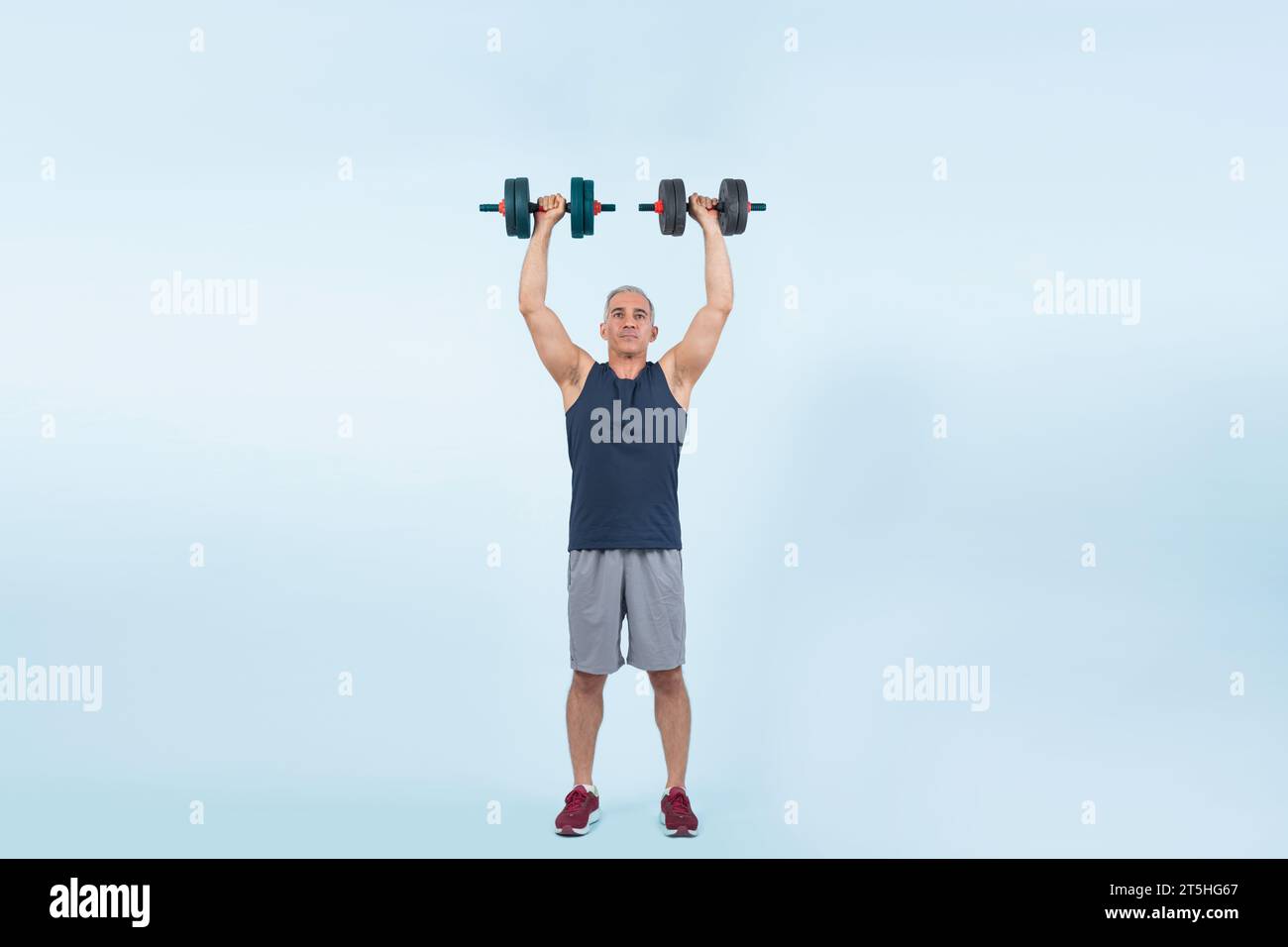 Full body length shot active and sporty senior man lifting dumbbell ...