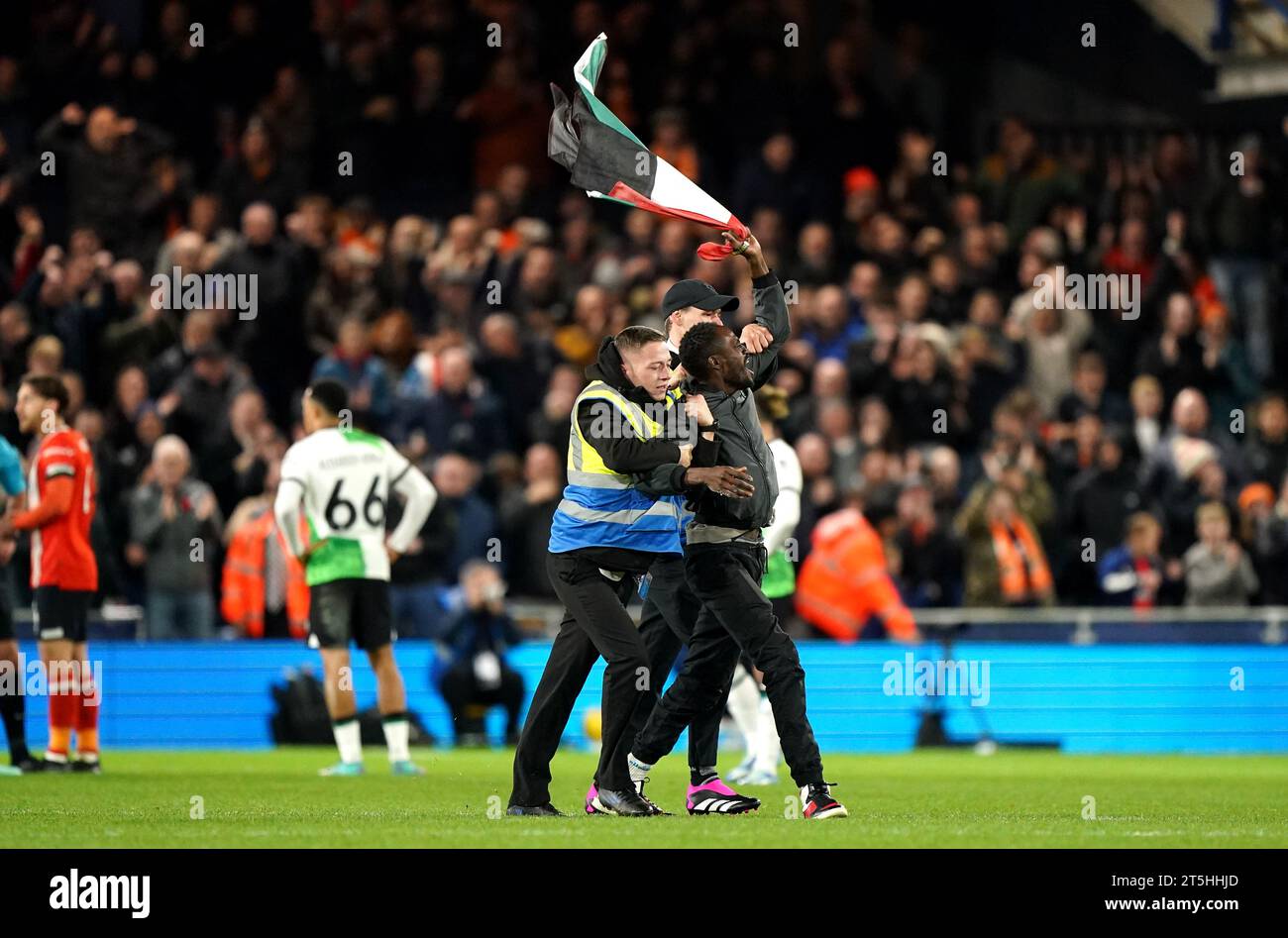A pitch invader holding a flag of Palestine is escorted off the field ...
