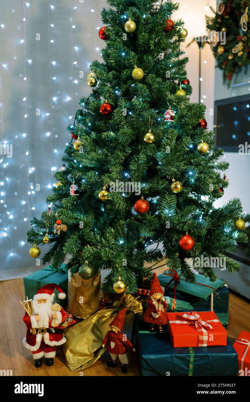 Colorful gifts with figurines of Santa and elves lie under the ...