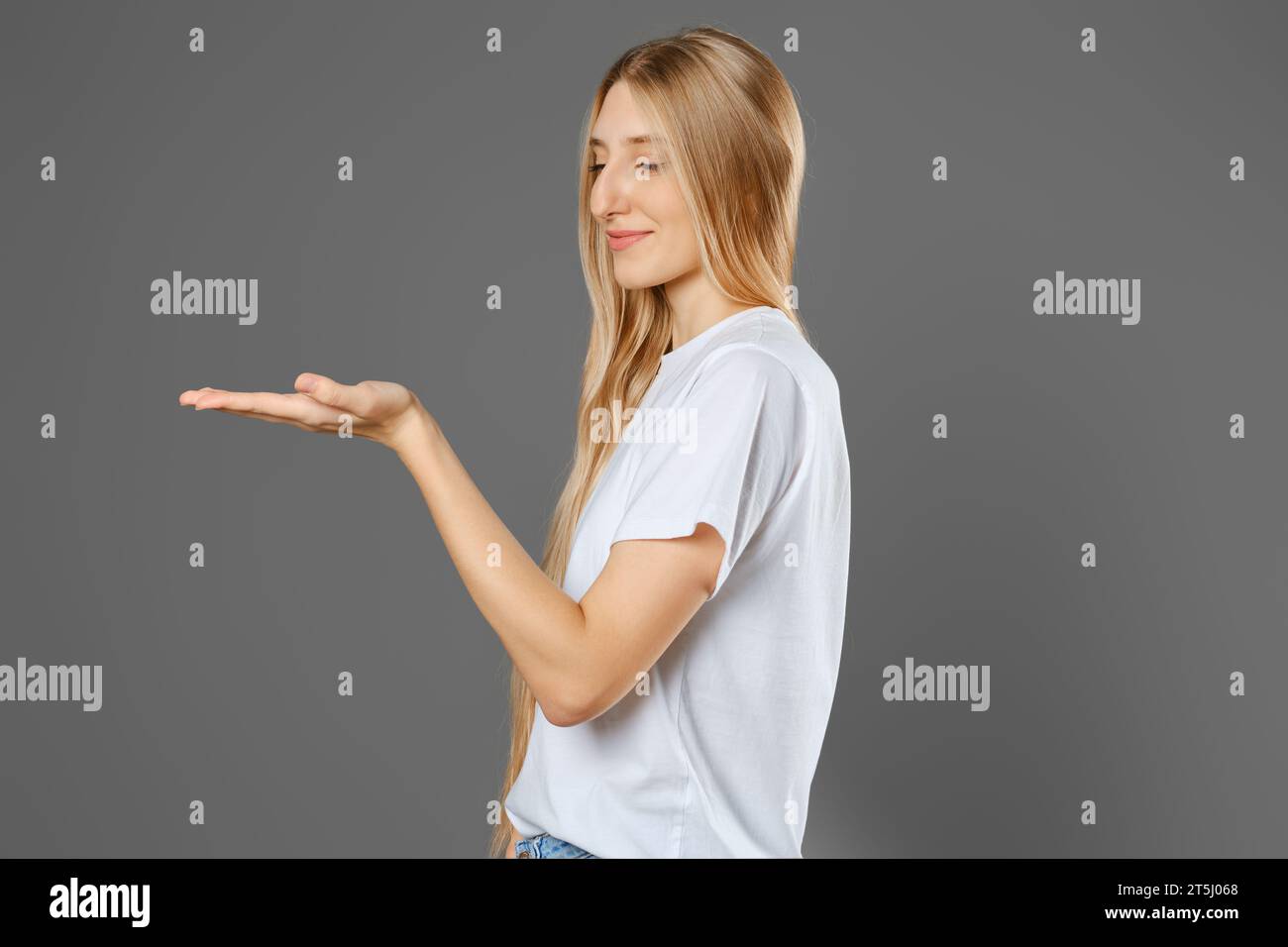 Nice woman stretched her hand forward with her palm up and looks at it ...