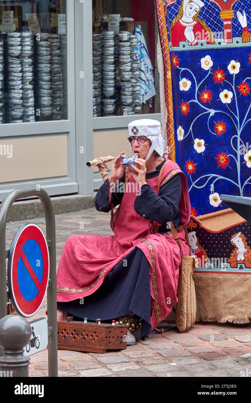 Street performer in medieval garments playing fife in Dinan, France ...