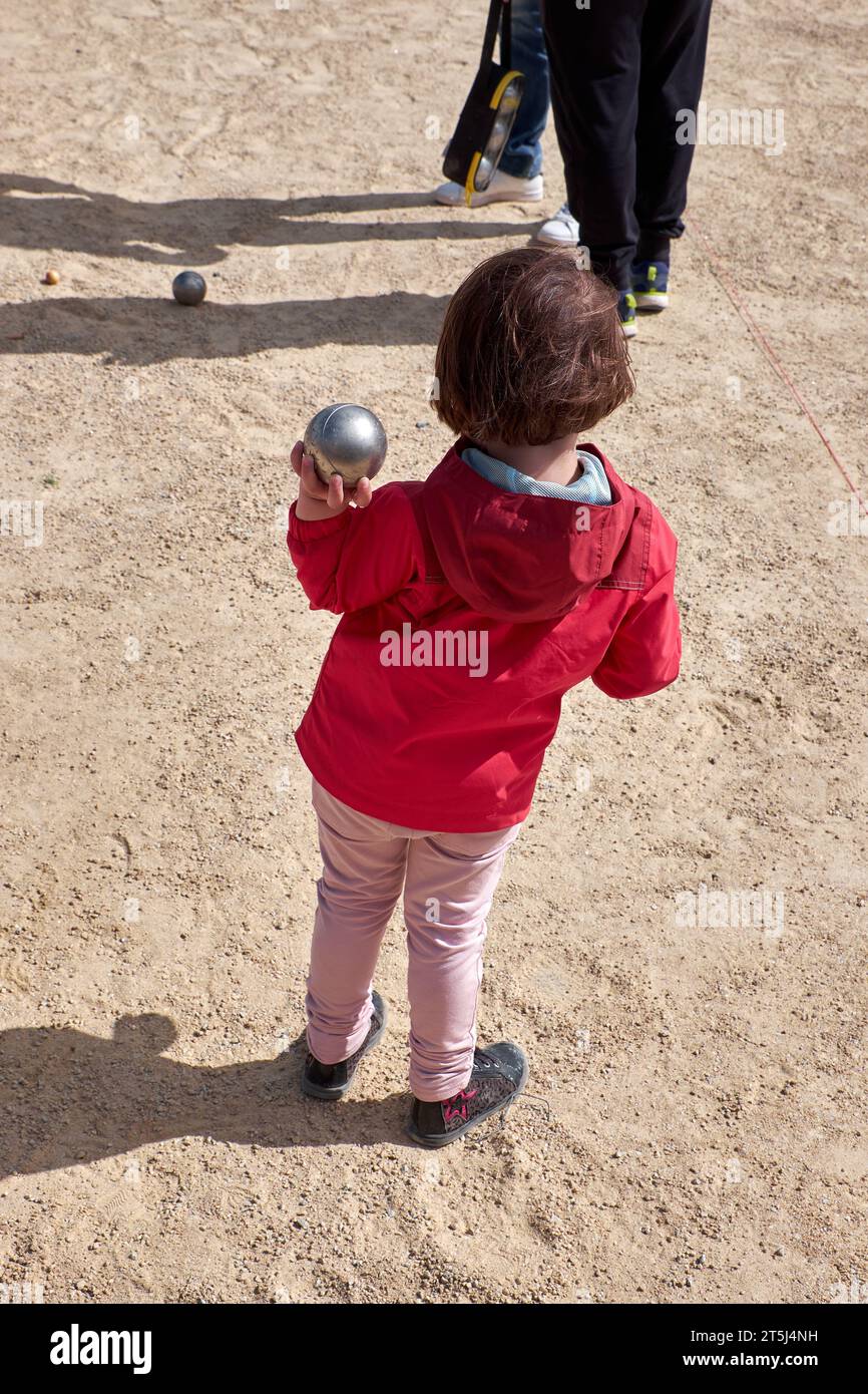 Little girl with a steel ball at a boules game ground Stock Photo - Alamy