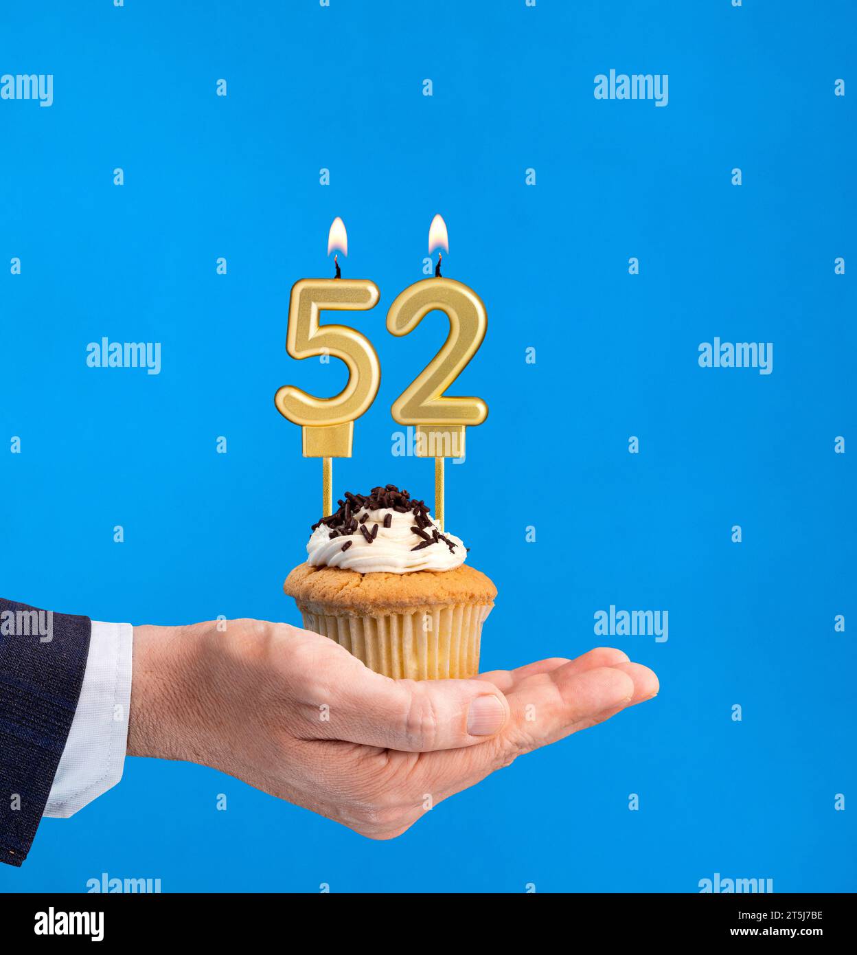 Hand delivering birthday cupcake - Candle number 52 on blue background ...