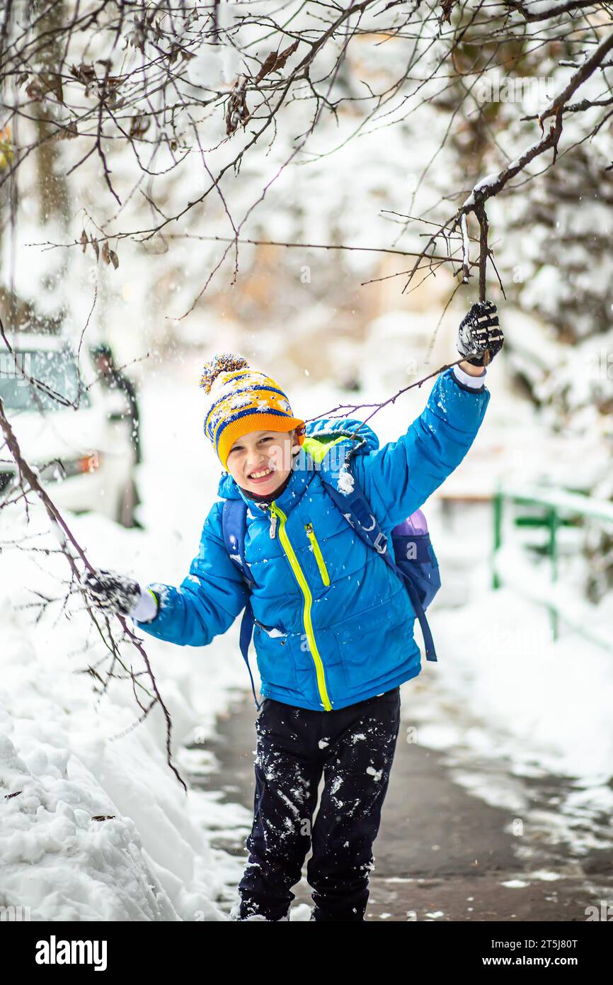 Boy student with backpack on shoulders having fun on snowy road ...