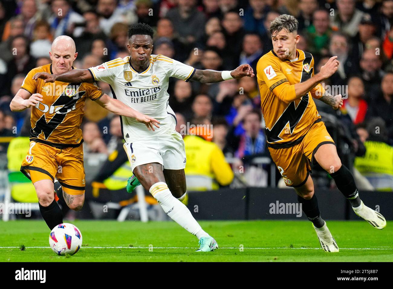 Real Madrid's Vinicius Junior, center, duels for the ball with Rayo's Isi Palazon, left, and ...